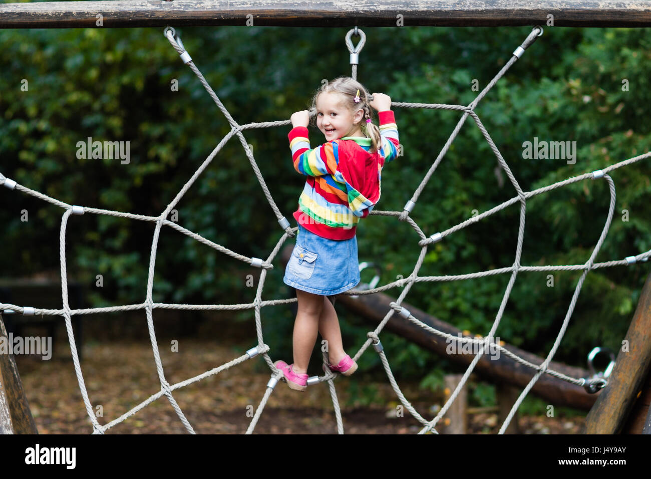 Active little child playing on climbing net and jumping on trampoline ...
