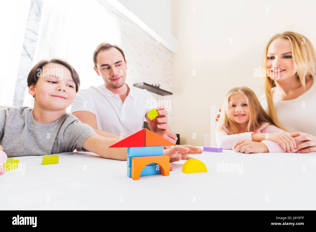 Family of four people with children constructing house of toy blocks ...