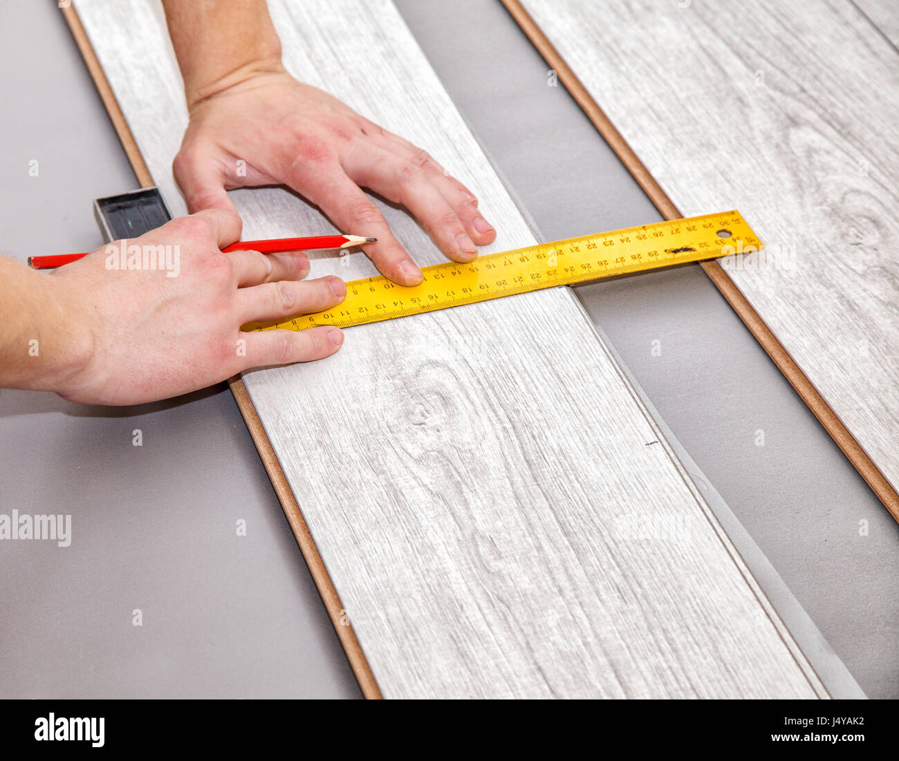 young handyman installing wooden floor in new house, hands closeup ...