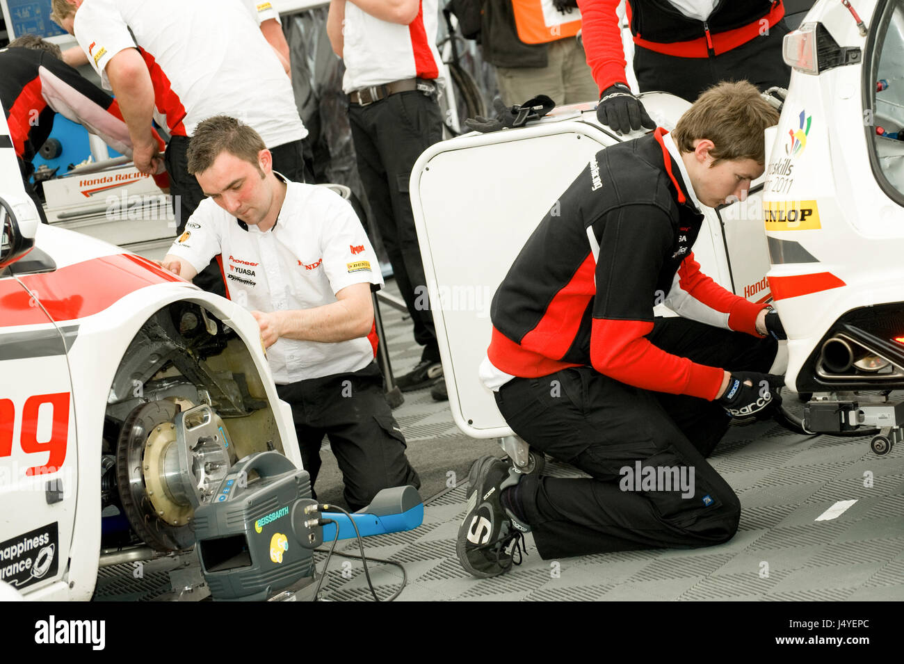 Mechanics from the Honda Yuasa racing team working on vehicles at the ...