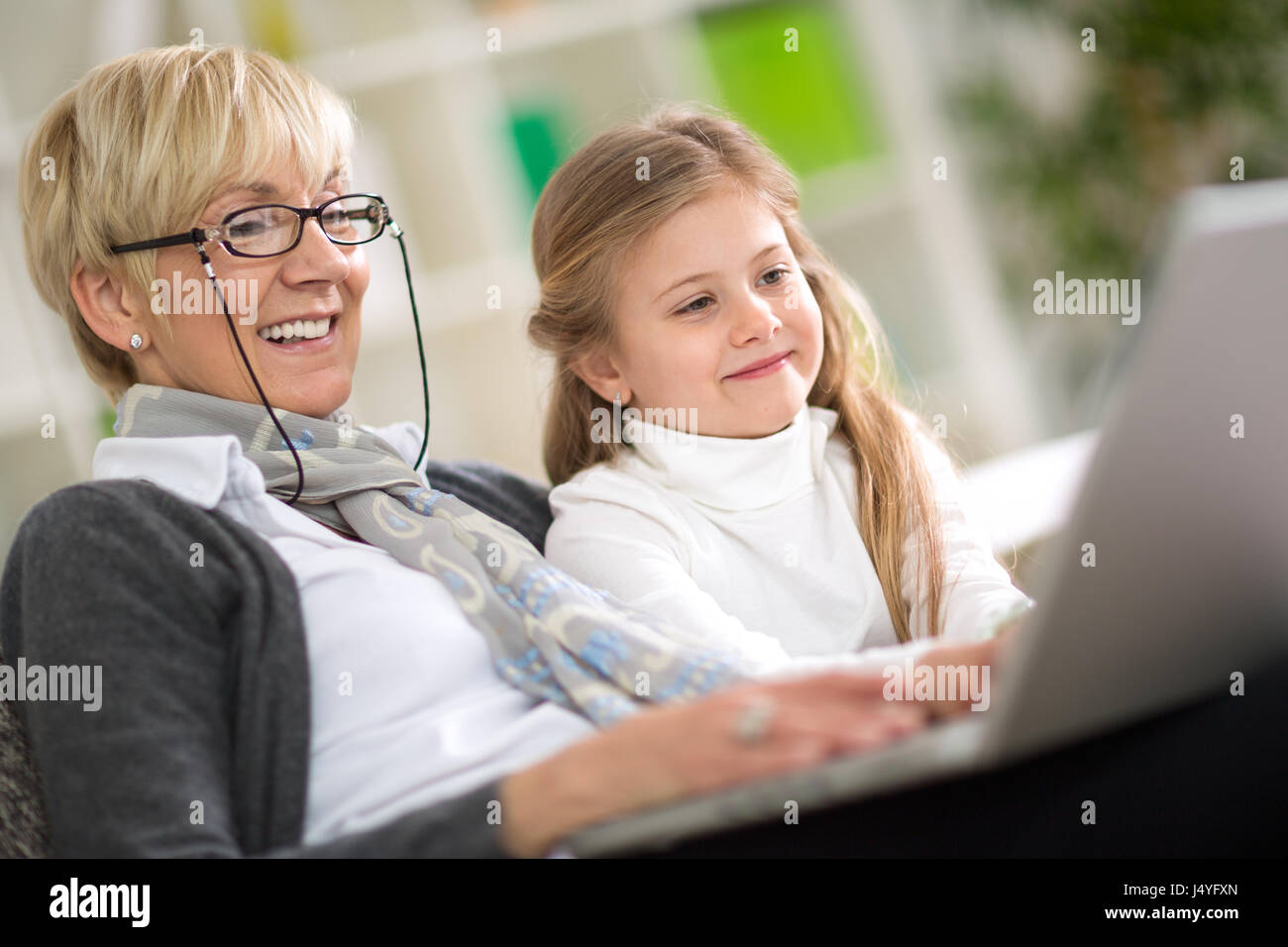 modern grandmother teaching grandchild how to use laptop computer at ...