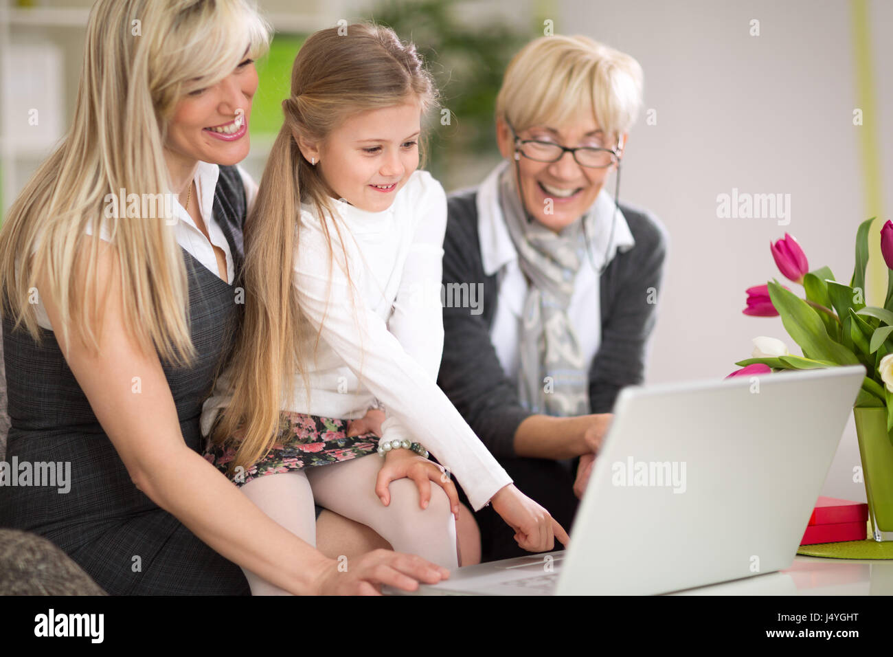 Little girl using laptop with mother and grandmother, modern technology ...