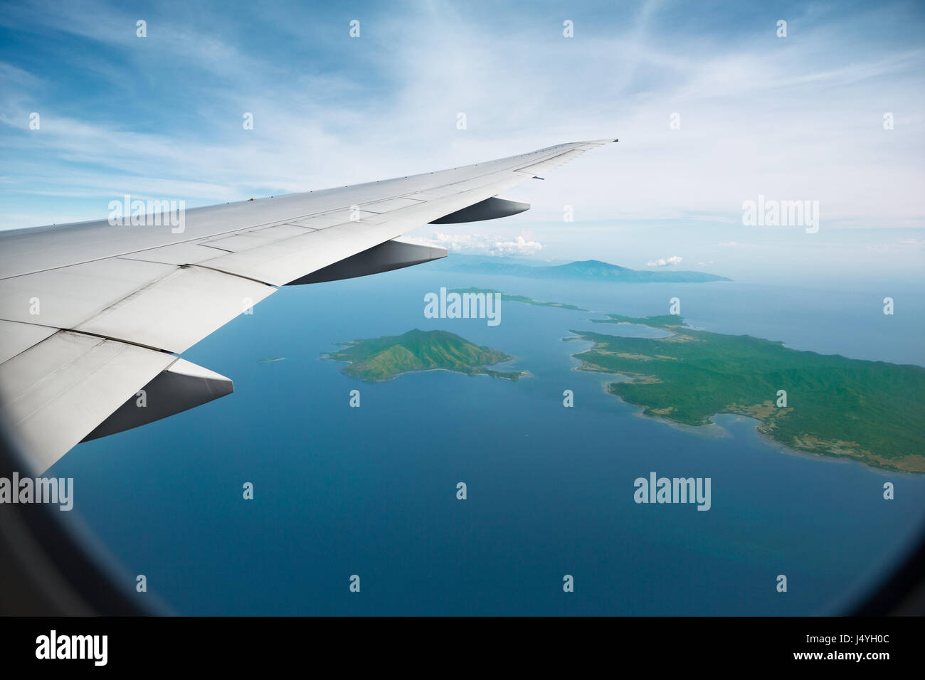 Aerial View of jet plane wing on ocean and island Stock Photo - Alamy