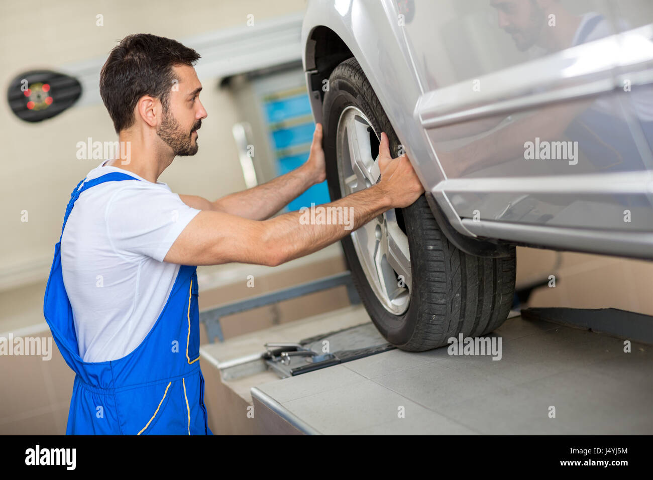 handsome mechanic changing a tire in workshop Stock Photo - Alamy