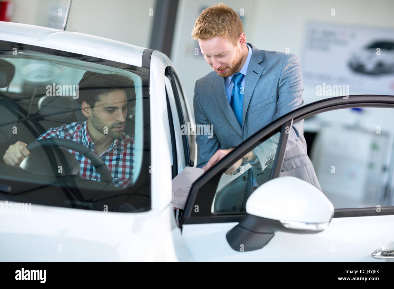 Car agent and customer in car showroom, together watching the ...