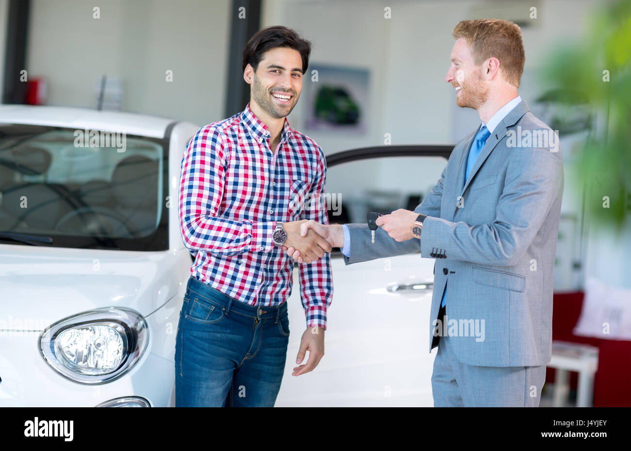 salesman and client at the car saloon, sitting, gesturing and ...