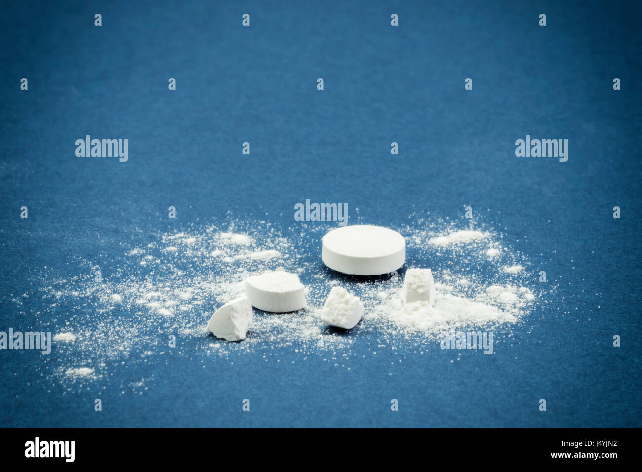 Still life of pills and its powder on blue background Stock Photo - Alamy
