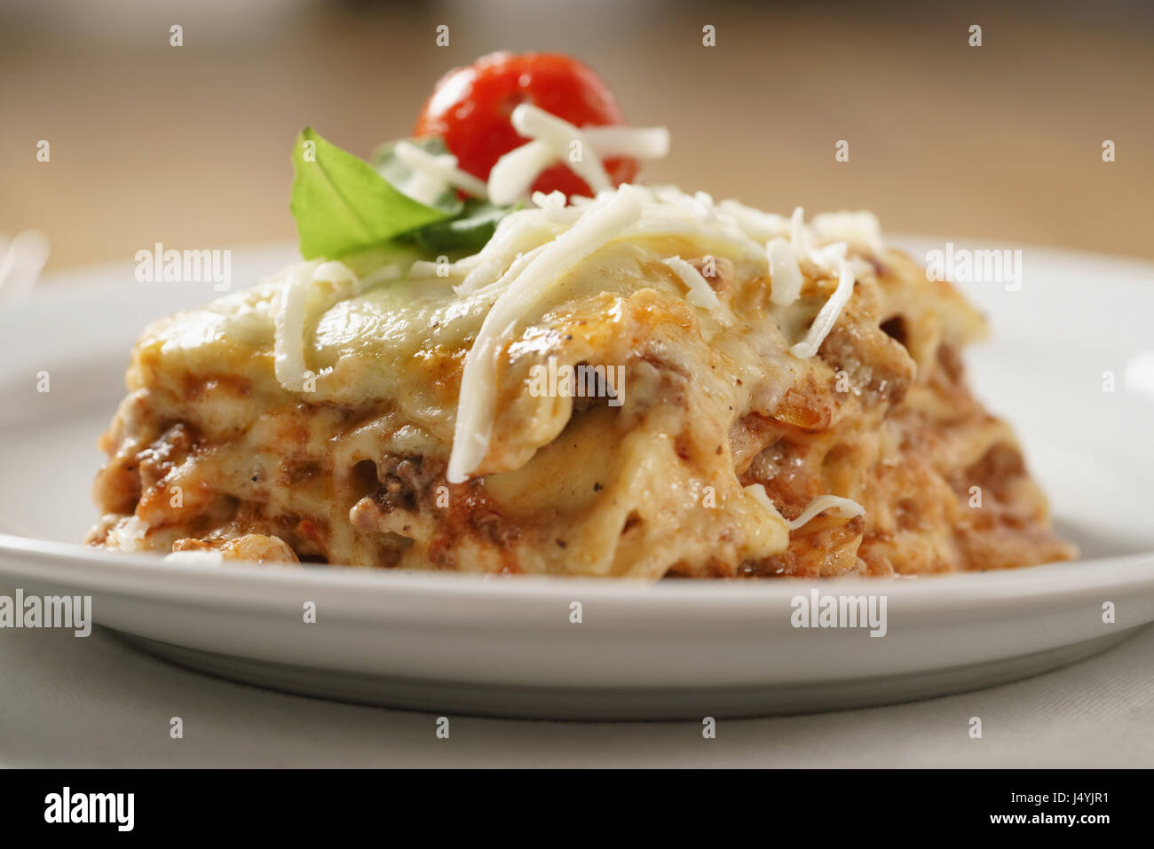 homemade lasagna portion on white plate on wood table Stock Photo - Alamy