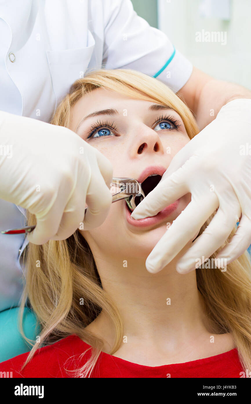 Closeup young woman at dentist clinic office. Male doctor and assistant ...
