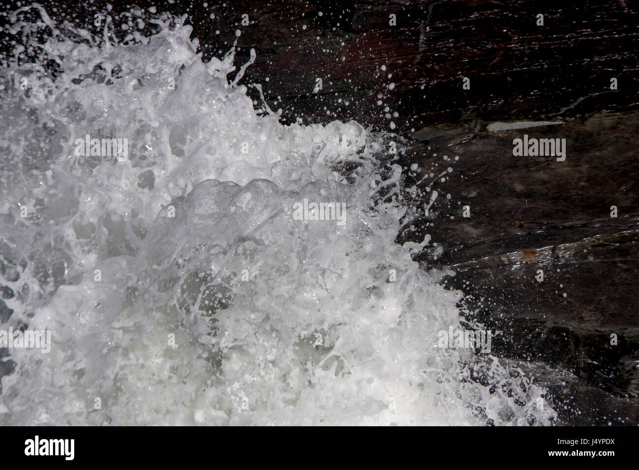 Breaking Wave Against Rocks Stock Photo - Alamy