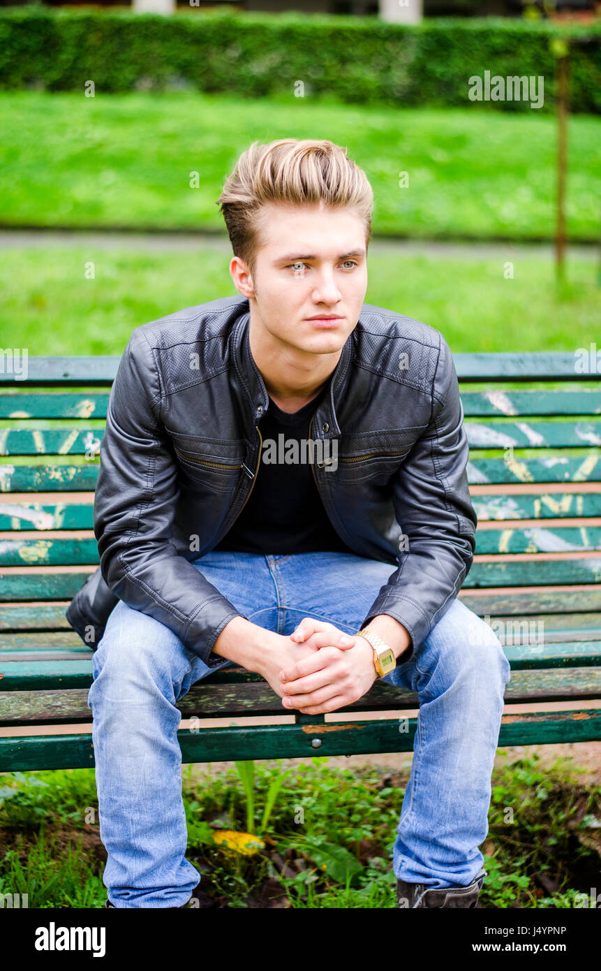 Handsome blond young man sitting on park bench Stock Photo - Alamy