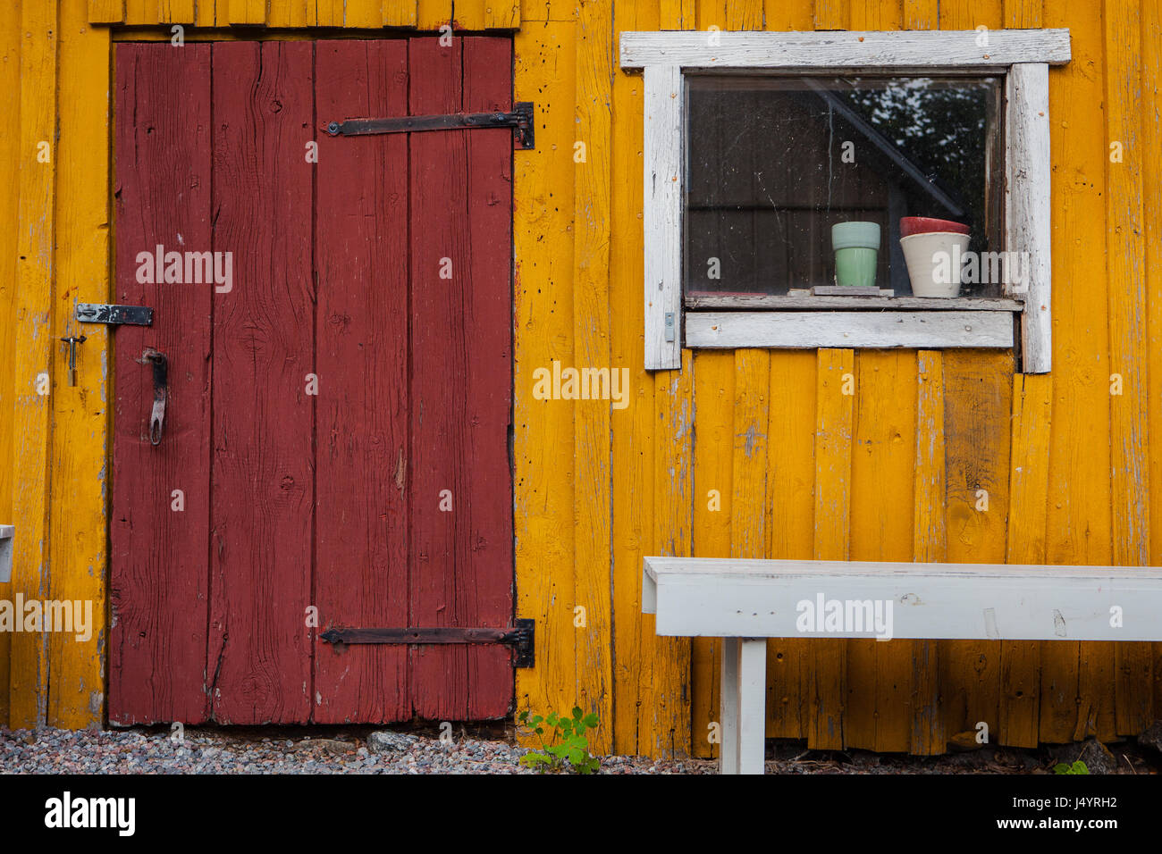 Rust-red door on golden yellow barn with bench in Sweden Stock Photo ...