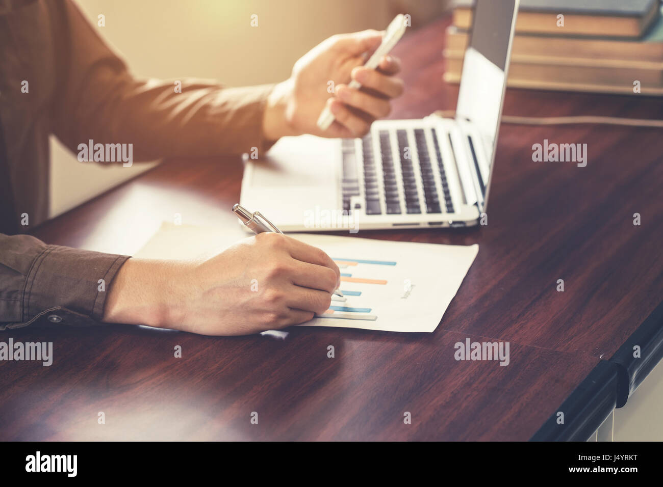Young business man hand using phone and writing paper in the office ...