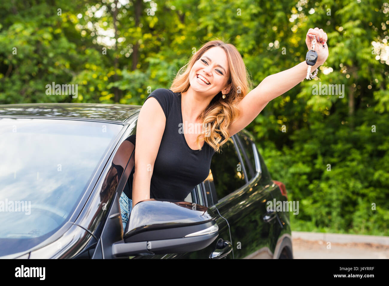 Young woman showing key in a car Stock Photo - Alamy
