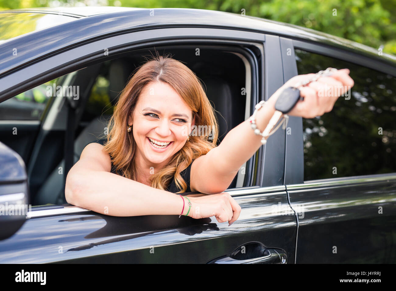 Young woman showing key in a car Stock Photo - Alamy