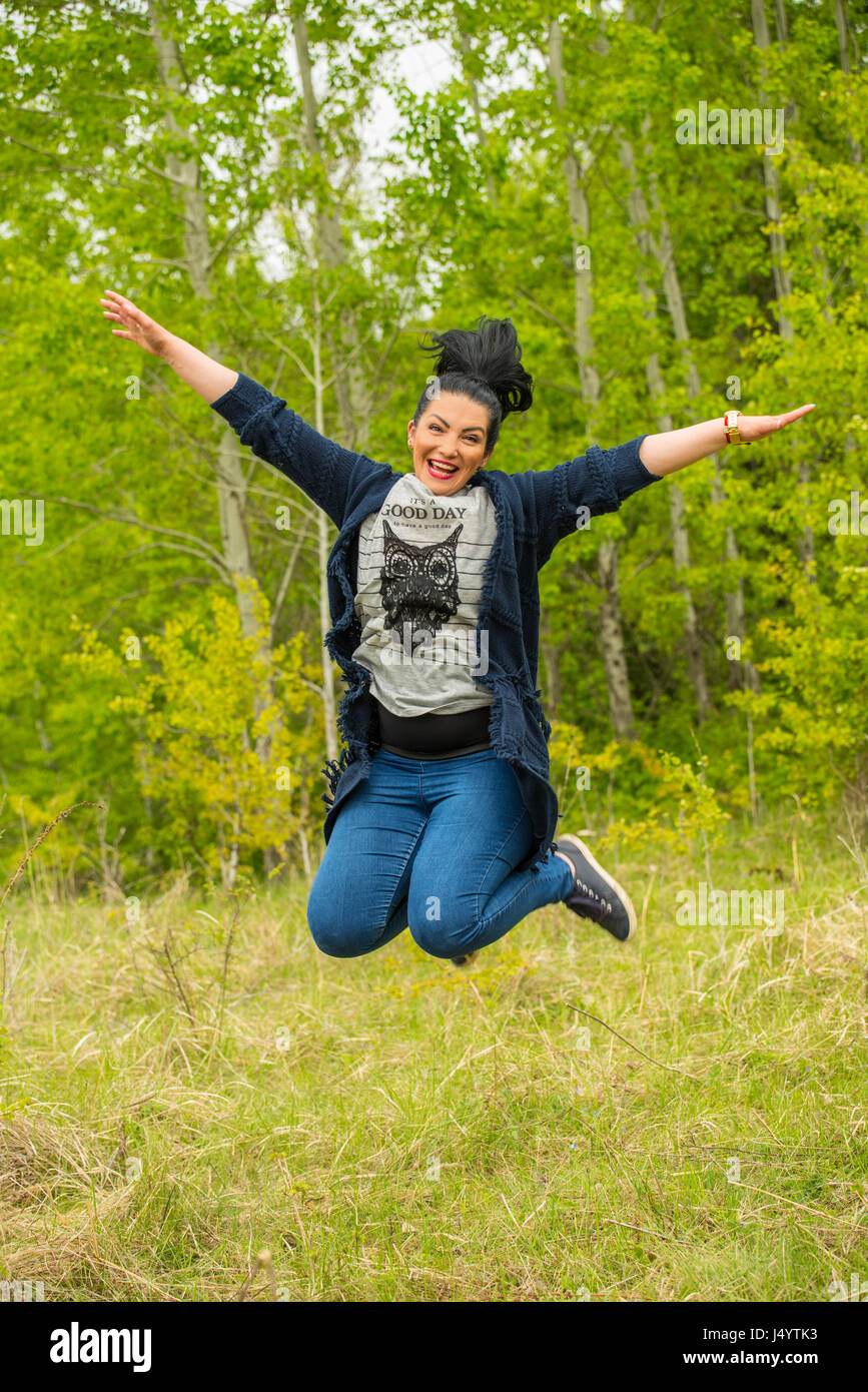 Laughing jumping woman in nature with forest in background Stock Photo ...