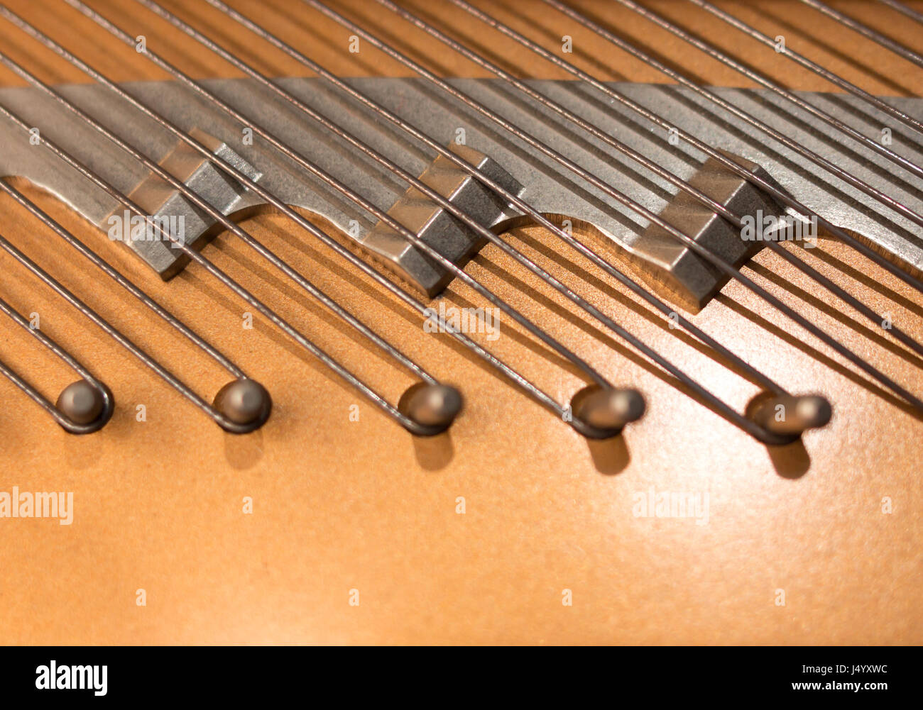 Piano treble strings hitch pins in line closeup Stock Photo - Alamy