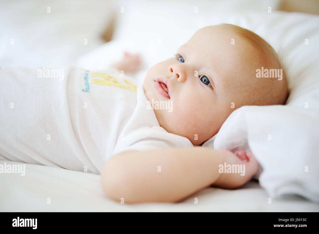 portrait of baby with blue eyes. A child resting on a bed Stock Photo ...