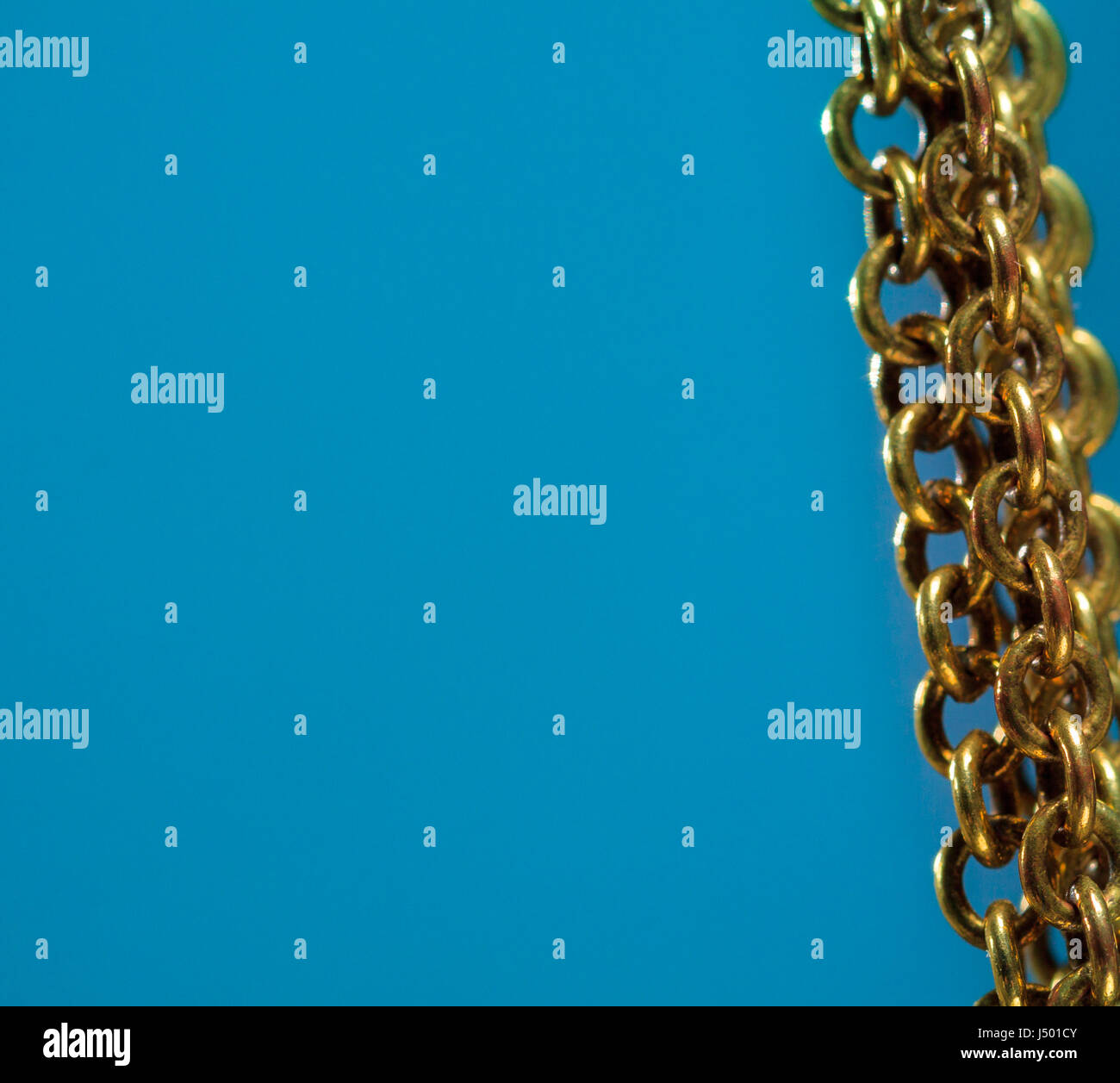 Gold chain on blue background right side of the photo Stock Photo - Alamy