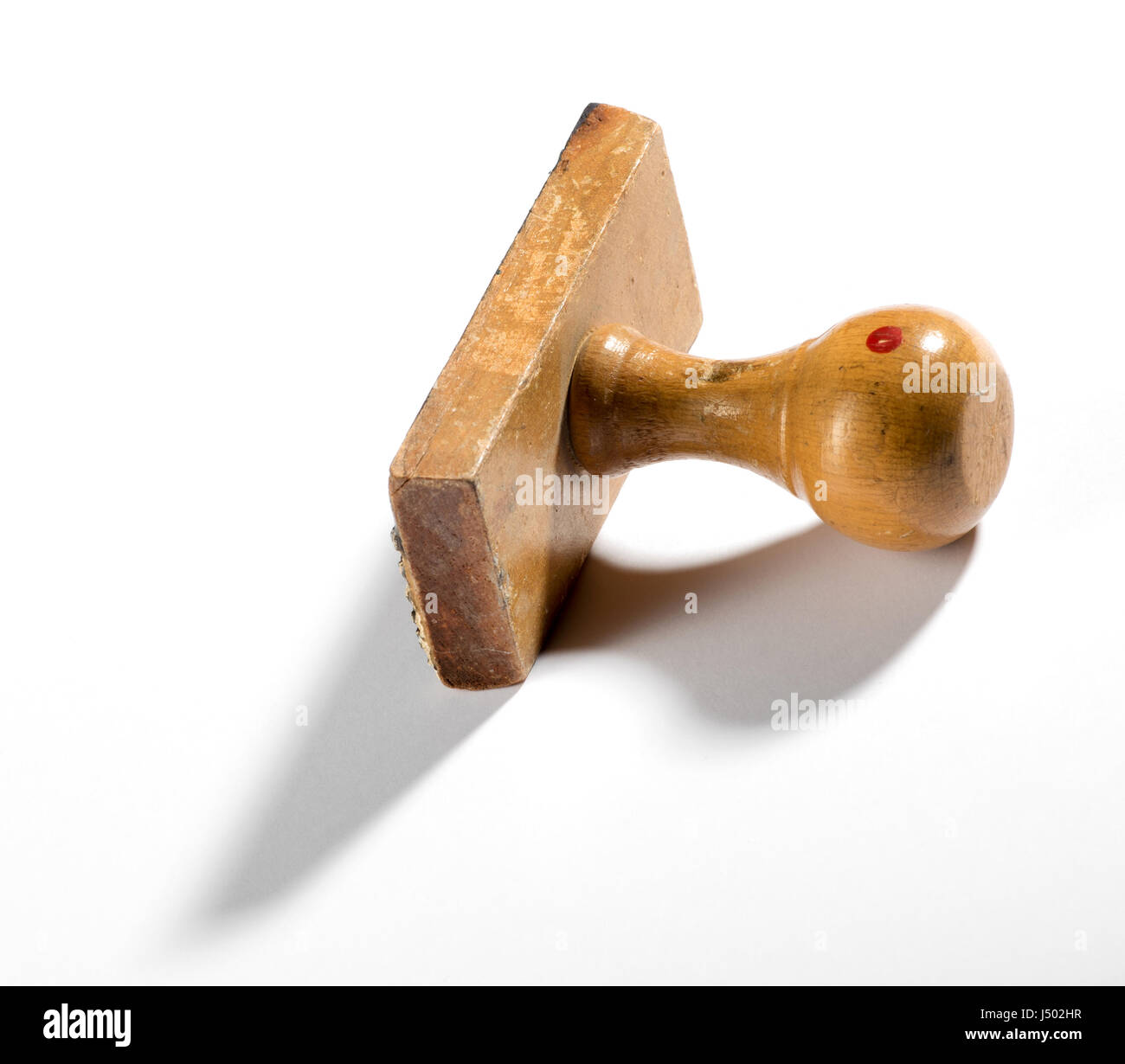 Wooden vintage rubber hand stamp laid on its side on white casting a ...