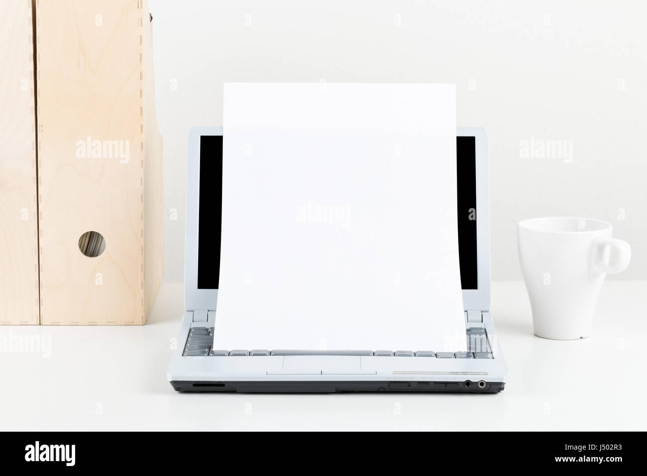 Empty sheet of paper as copy space in front of laptop on white ...