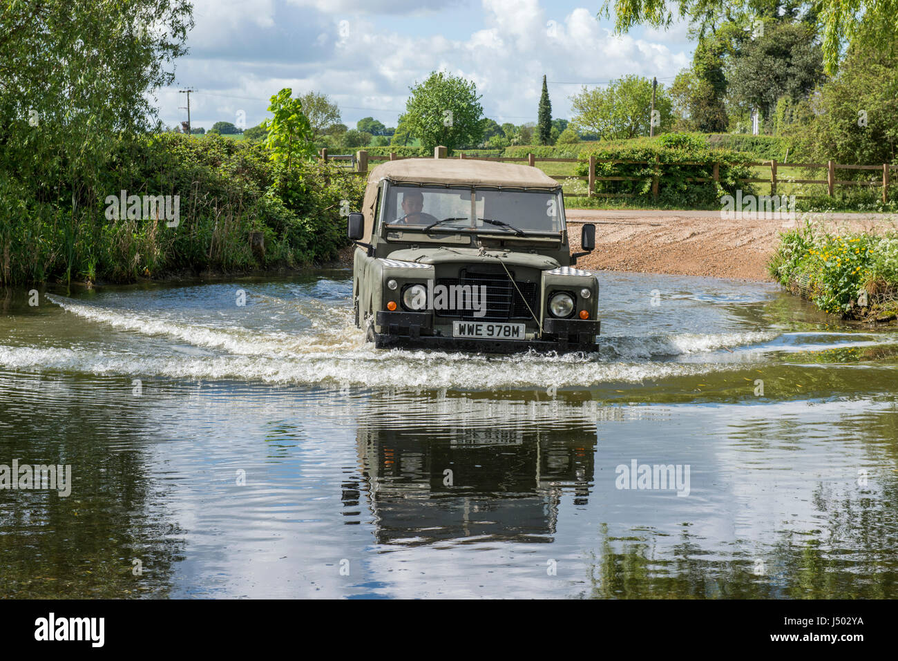 Model released image of a man driving a 1973 ex army Land Rover Series ...