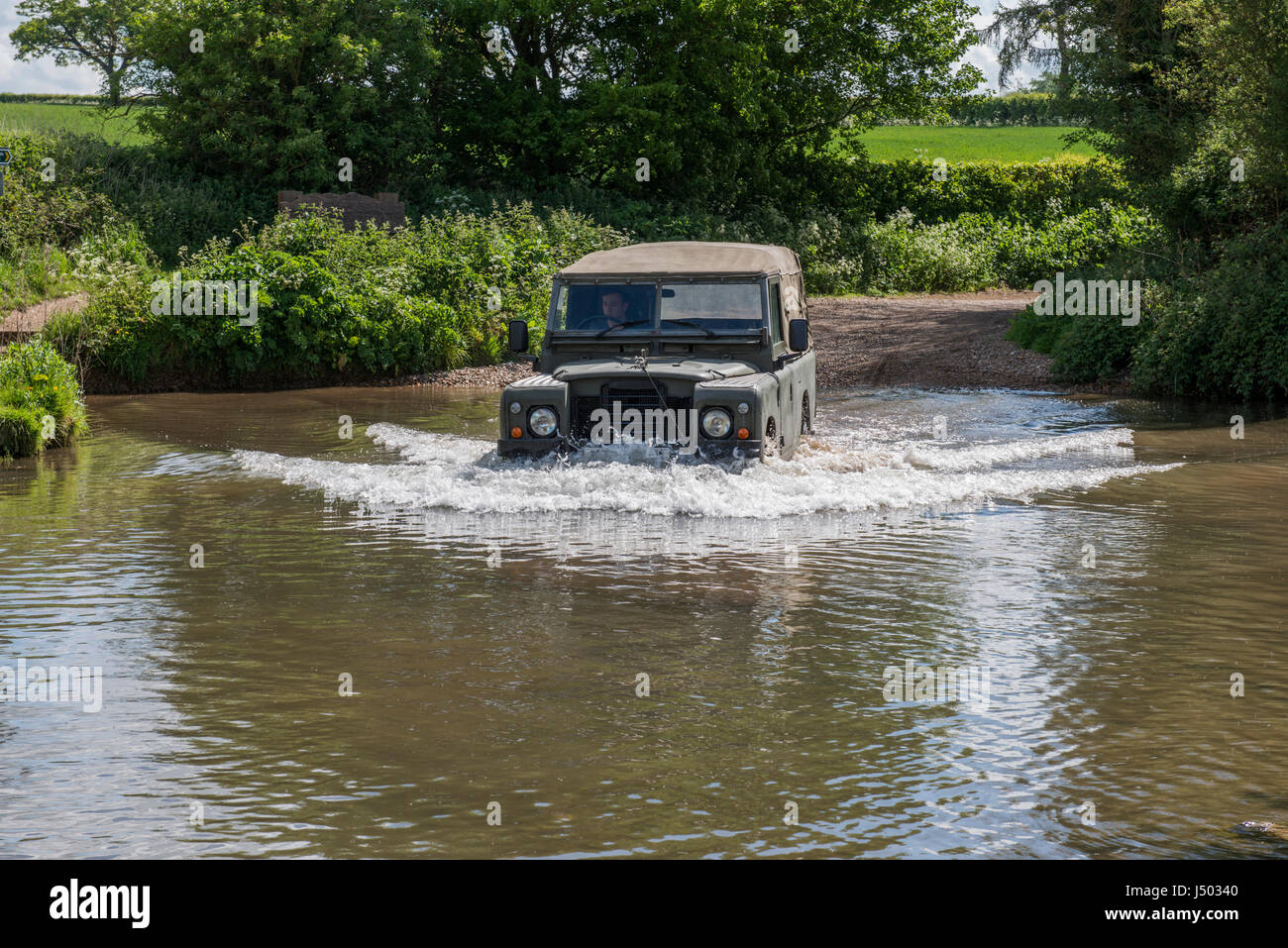 Model released image of a man driving a 1973 ex army Land Rover Series ...