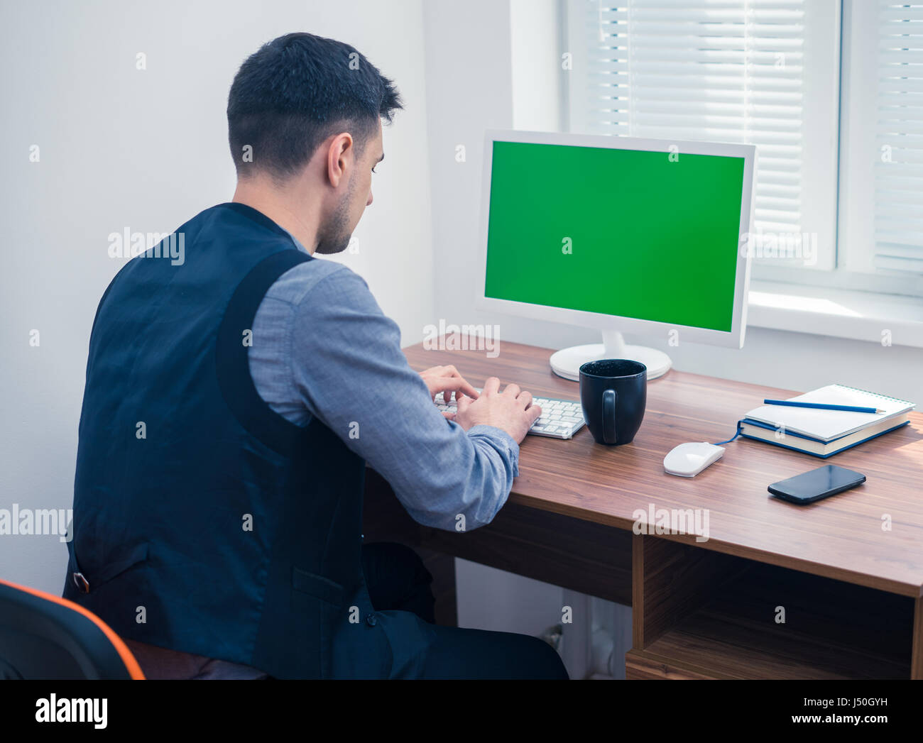 office worker sitting at computer with Chromakey on monitor Stock Photo ...