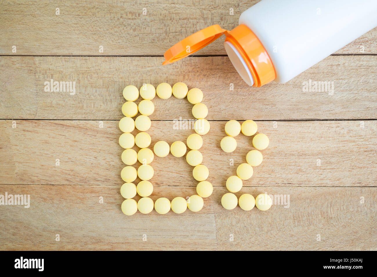 Yellow pills forming shape to B2 alphabet on wood background Stock ...