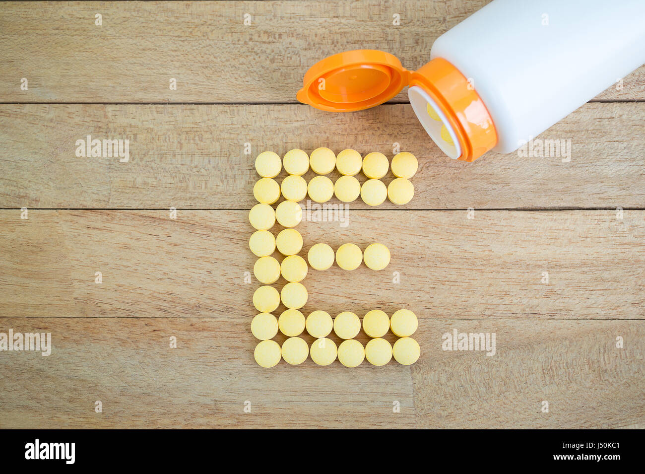 Yellow pills forming shape to E alphabet on wood background Stock Photo ...
