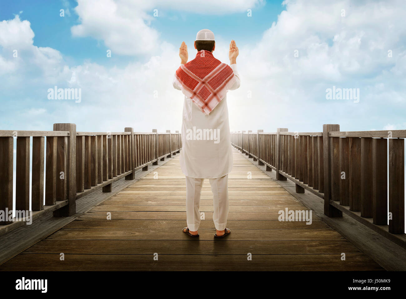 Back view of asian muslim man standing and praying over blue sky ...
