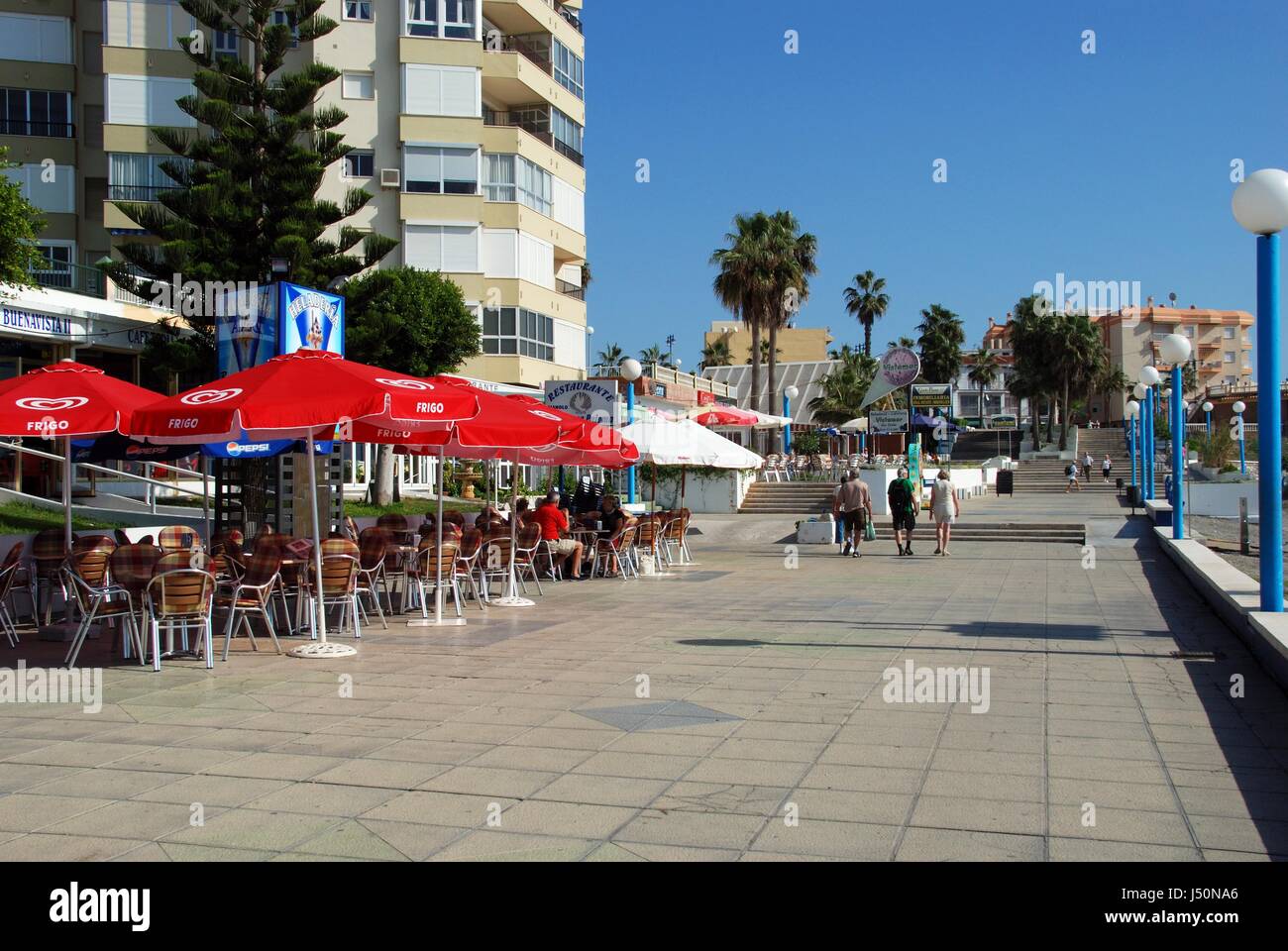 Tourists walking along the promenade with pavement cafes to the left ...