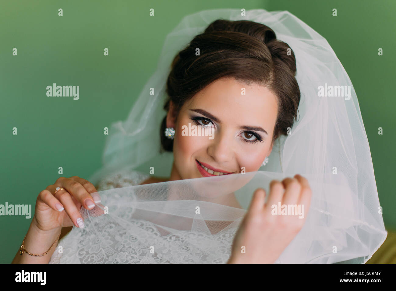 Beautiful young playful bride hiding her face behind veil Stock Photo ...