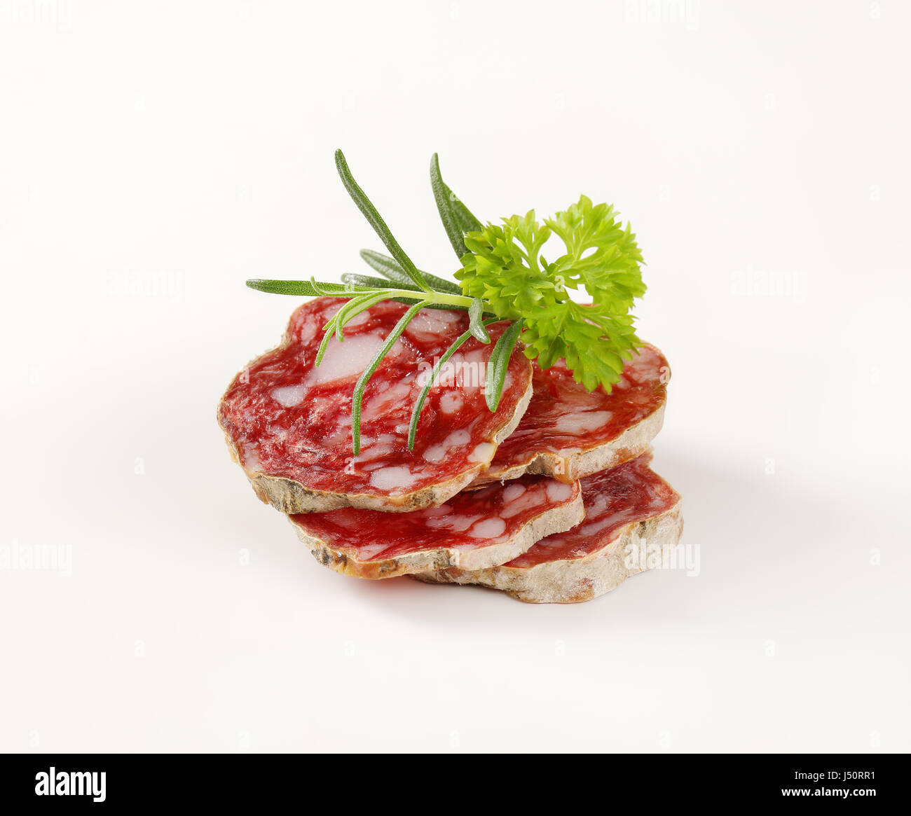 slices of French dry cured salami with herbs on white background Stock ...