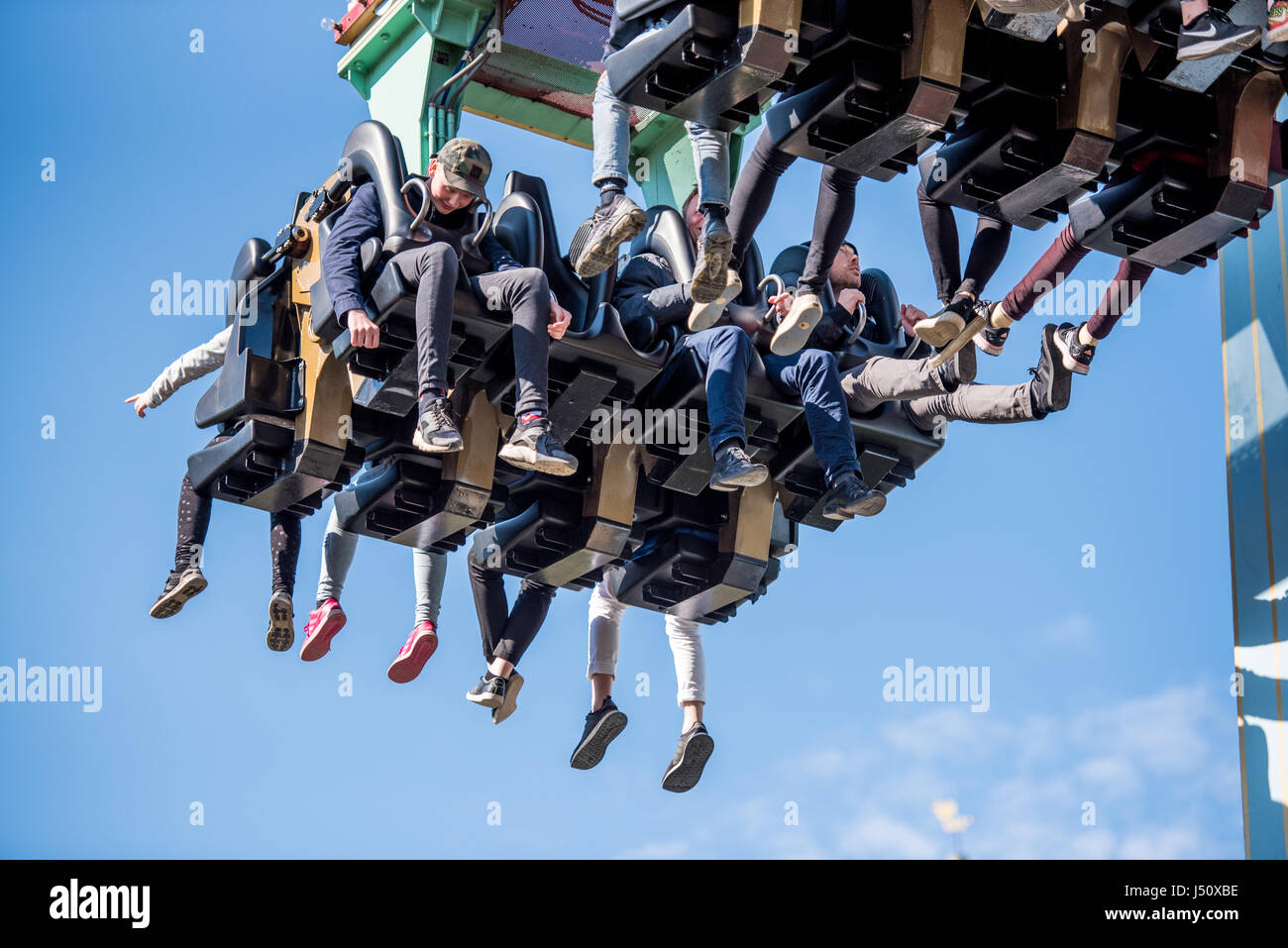 Enthusiastic young friends riding roller coaster ride at amusement park ...