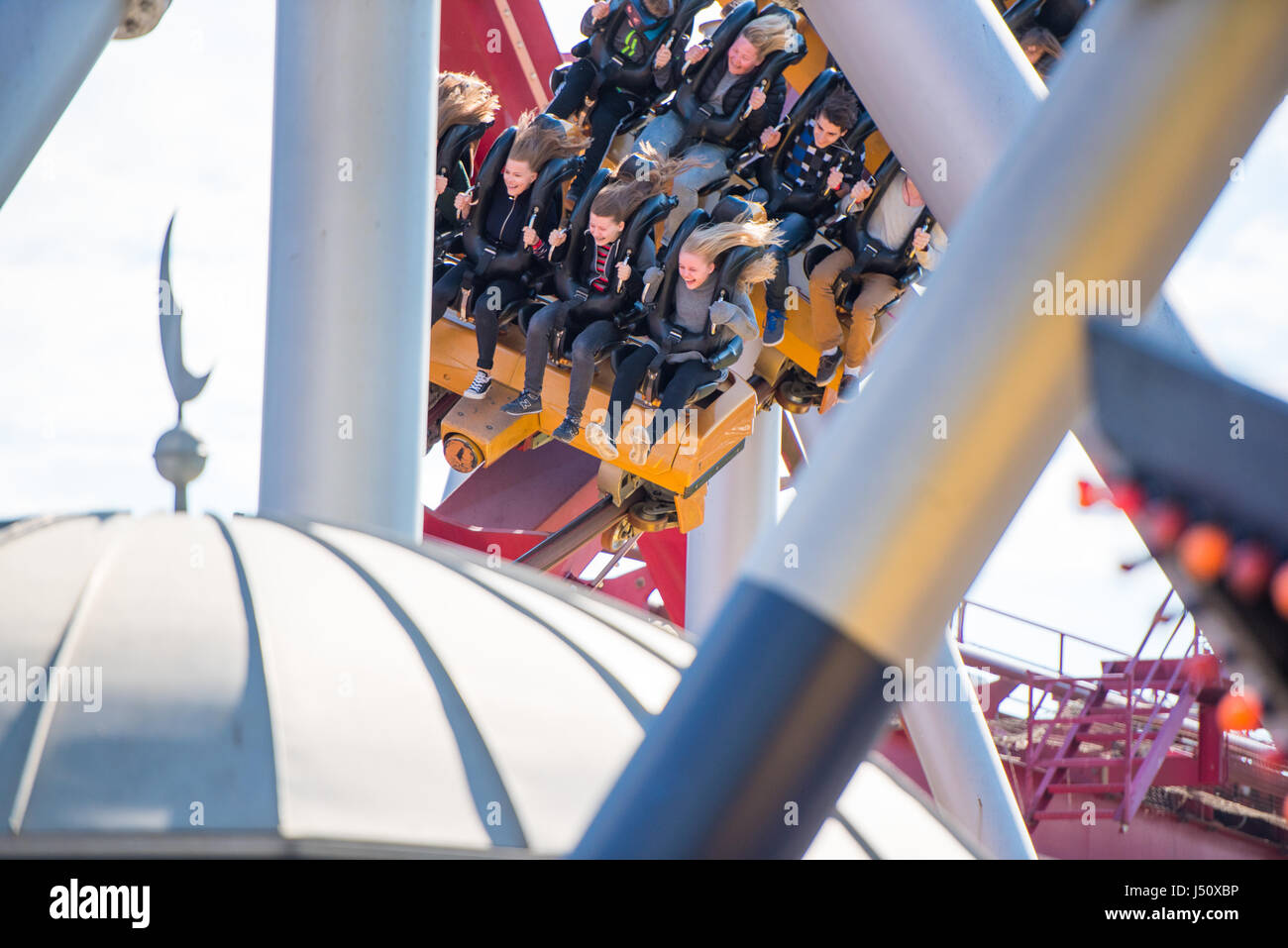 Enthusiastic young friends riding roller coaster ride at amusement park ...