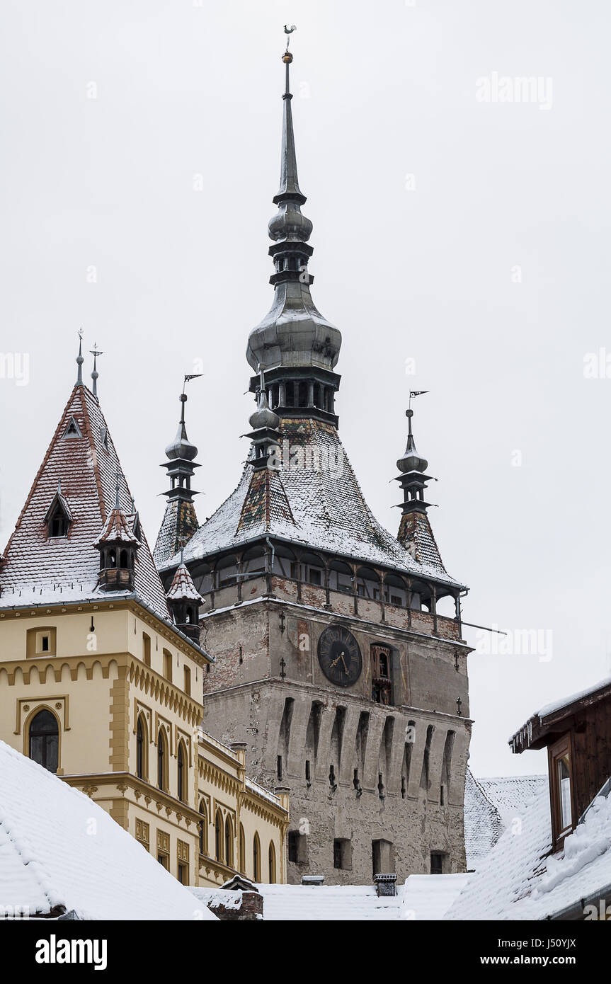 Weathered ancient clock tower of an old fortress. Roof tops and a ...
