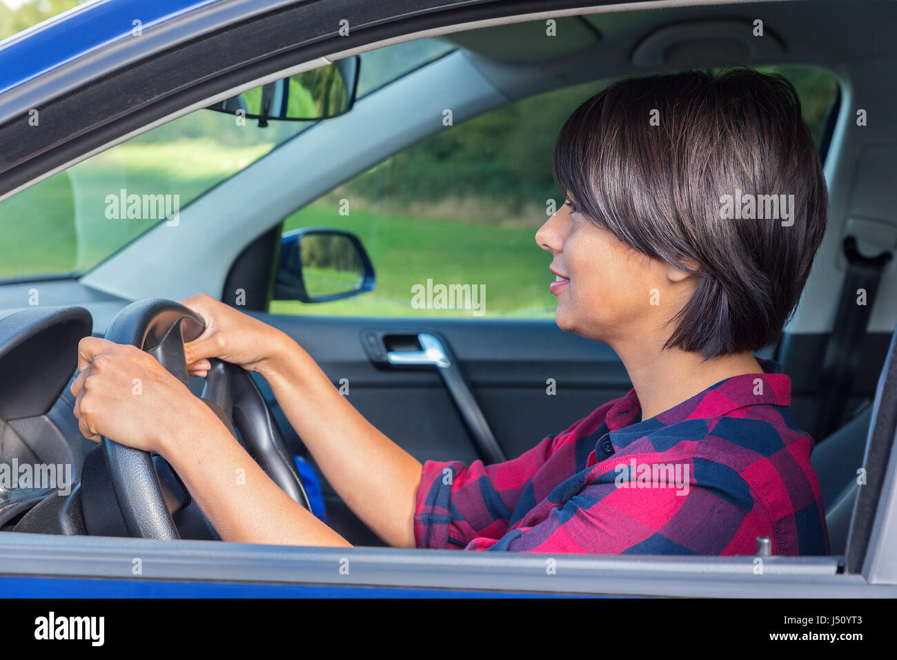 Colombian woman behind steering wheel in car Stock Photo - Alamy