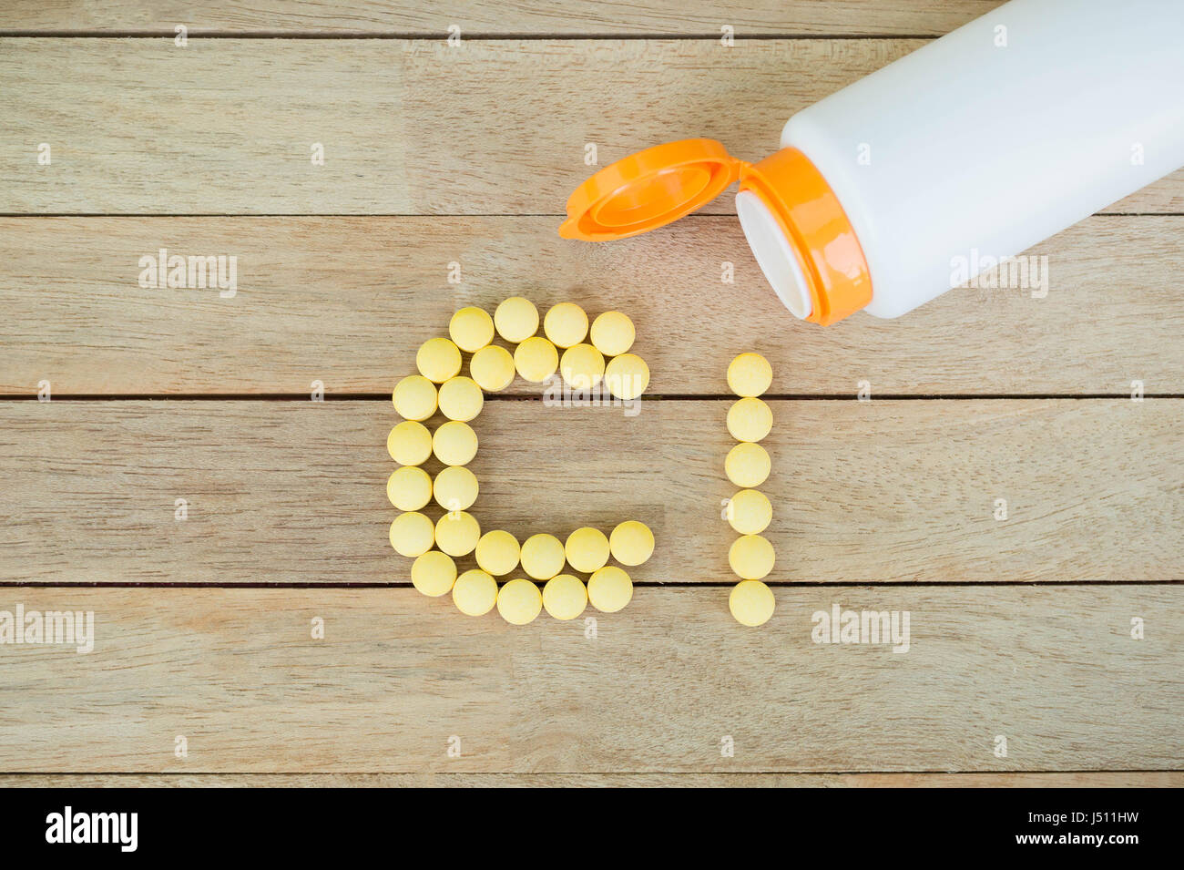 Yellow pills forming shape to Cl alphabet on wood background Stock ...