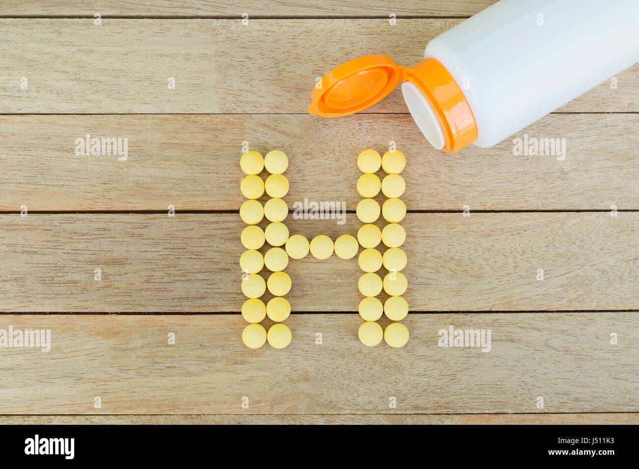 Yellow pills forming shape to H alphabet on wood background Stock Photo ...