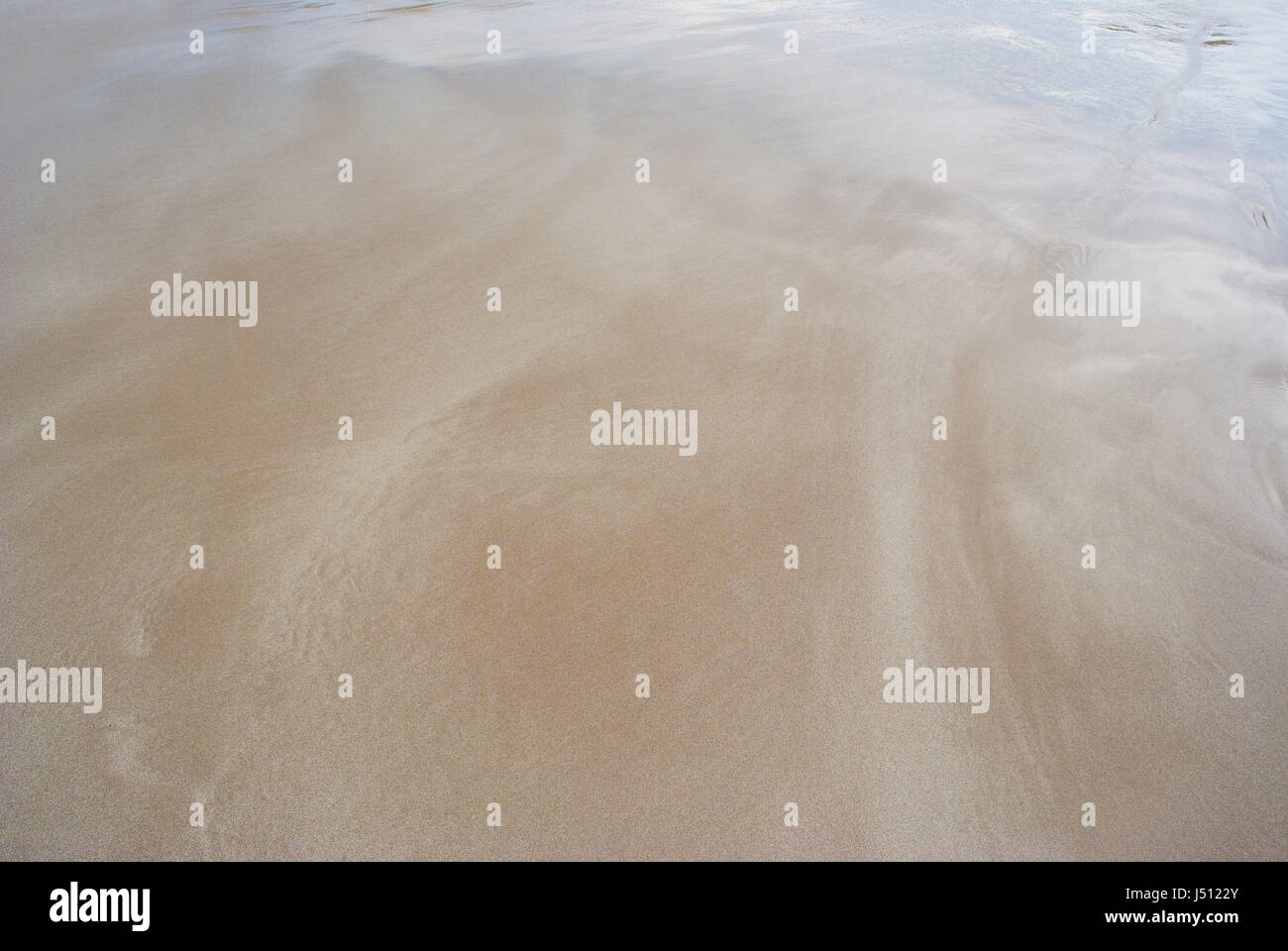 Smooth, calming patterns of the water flowing through the wet sand at ...