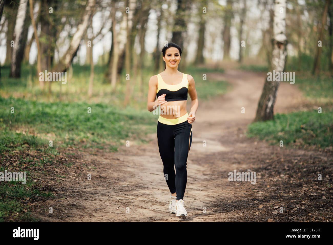 Fit young woman running in spring park Stock Photo - Alamy