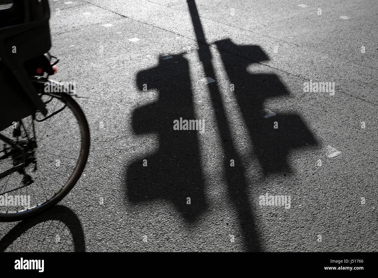 Shadow of traffic lights on tarmac road with cyclist bicycle wheel in a ...