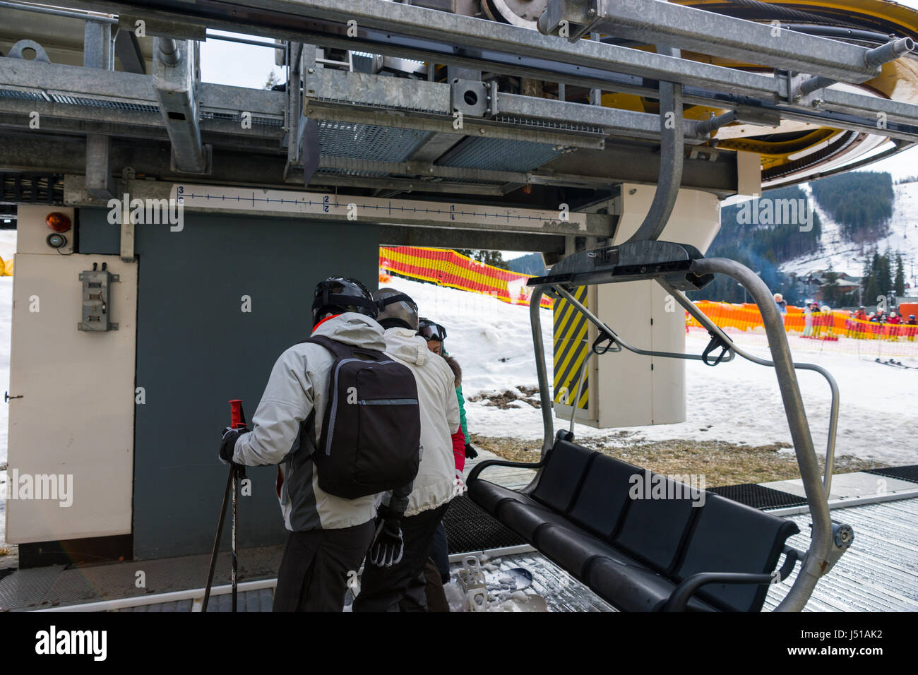 A group of people sitting down on ski lift with seats in a ski-resort ...