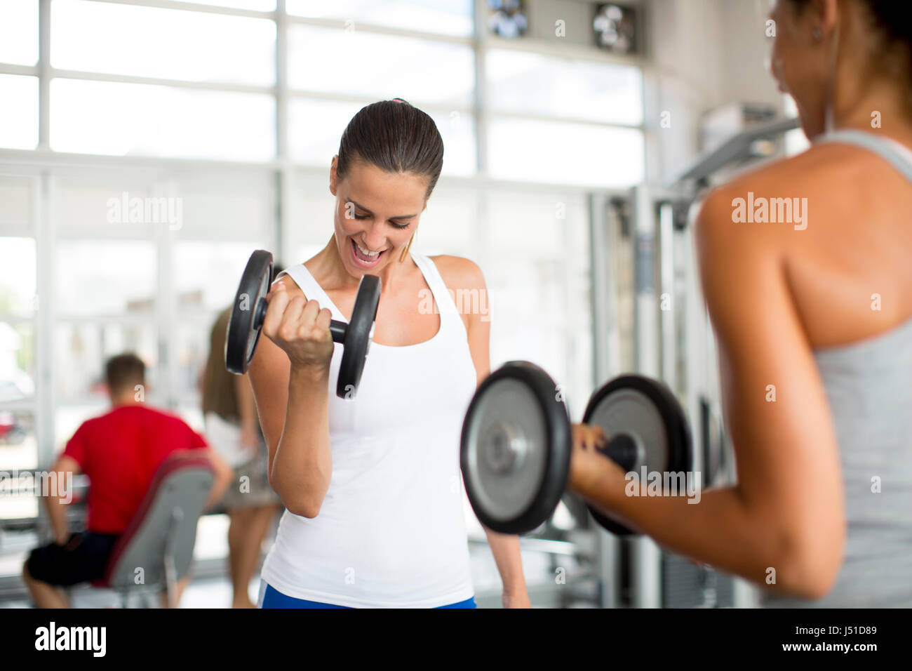 Two young women exercising lifting weights in the modern gym Stock ...