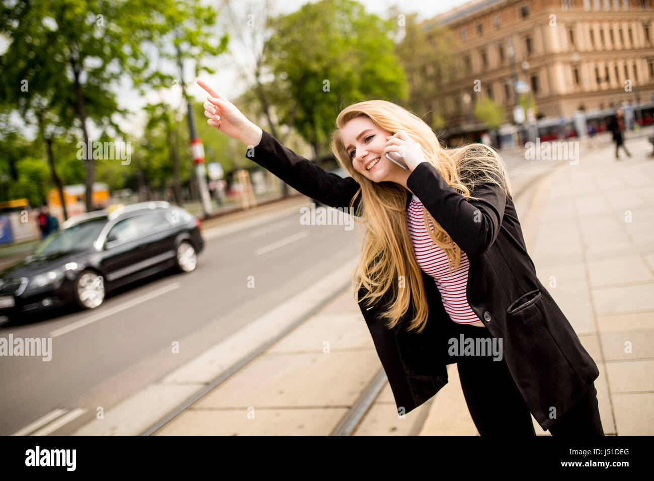 View at young woman hailing a taxi on the street in the city Stock ...