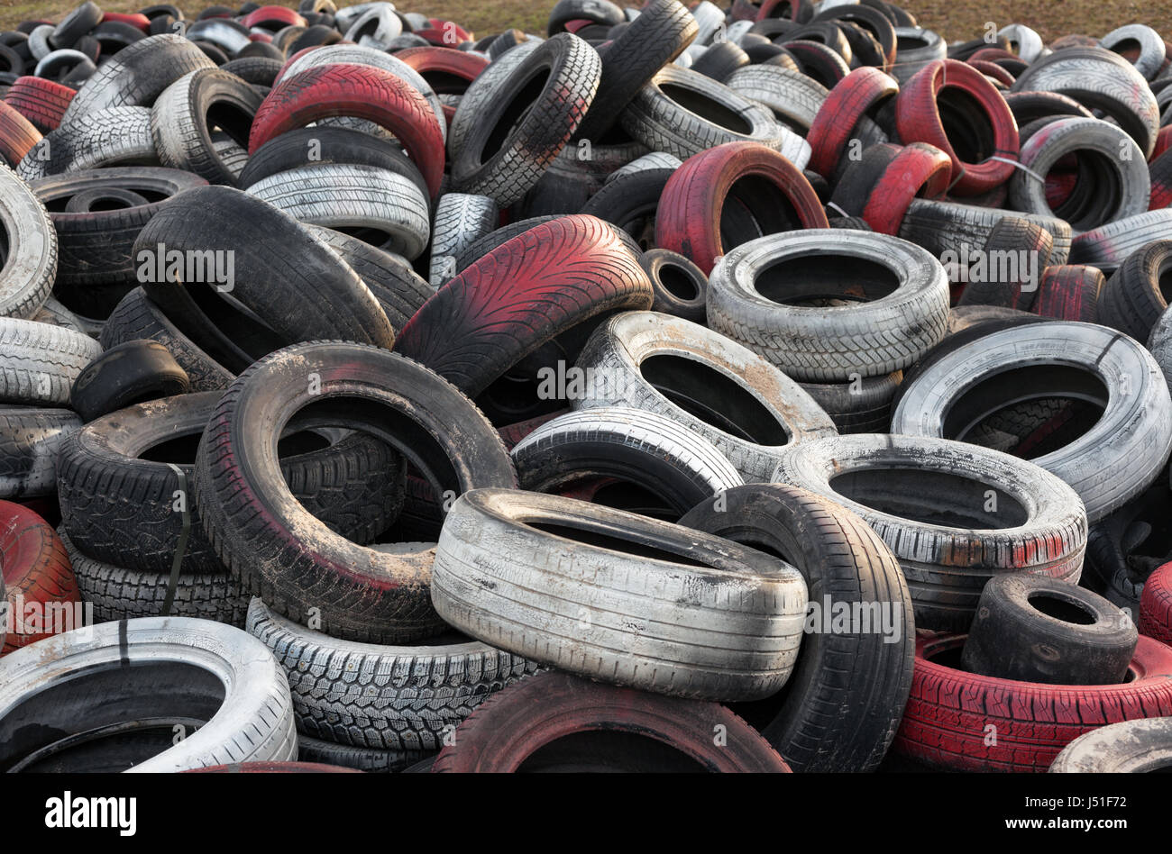 Variety of red white and black waste car tires piled in a big pile ...