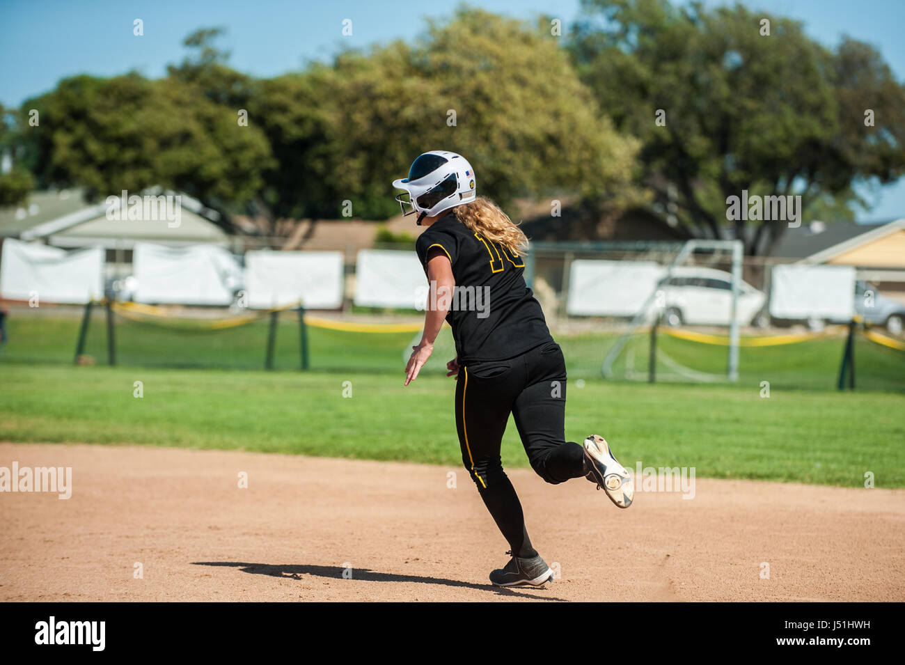 Black uniform softball player running hard for second base Stock Photo ...