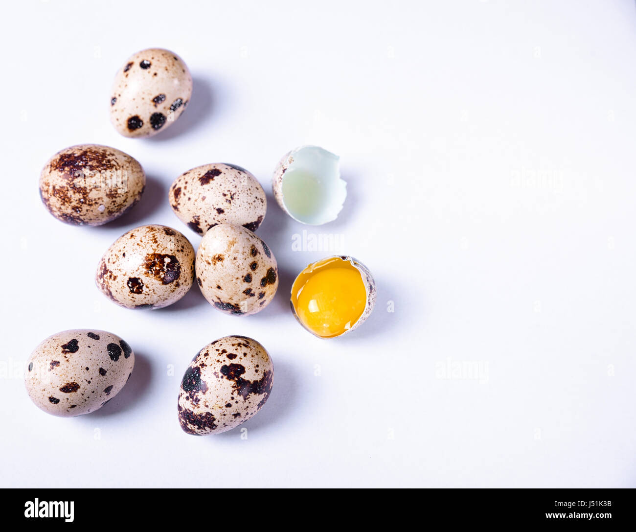 Fresh quail eggs in the shell, one egg is broken, white surface, empty ...