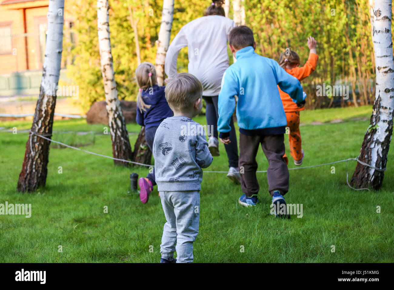Children playing in a garden. They are jumping over the rope between ...